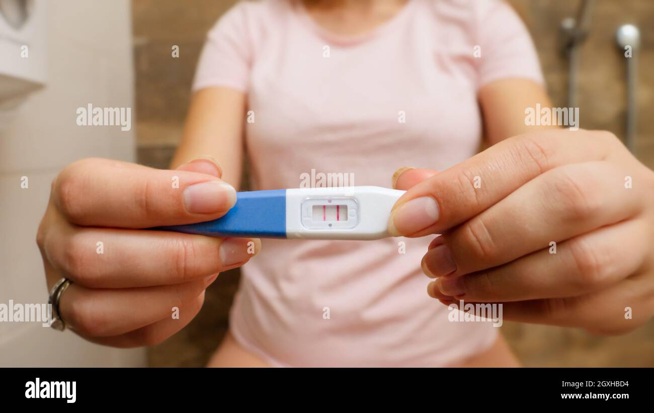 Closeup of woman holding positive pregnancy test and showing it in ...