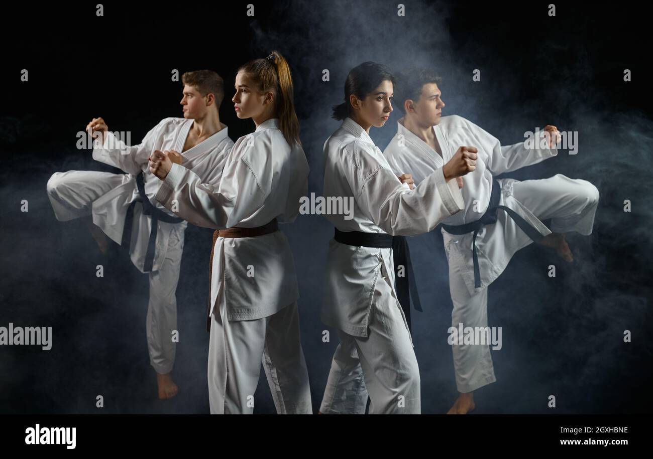 Four karate fighters in white kimono, group training, dark smoky ...