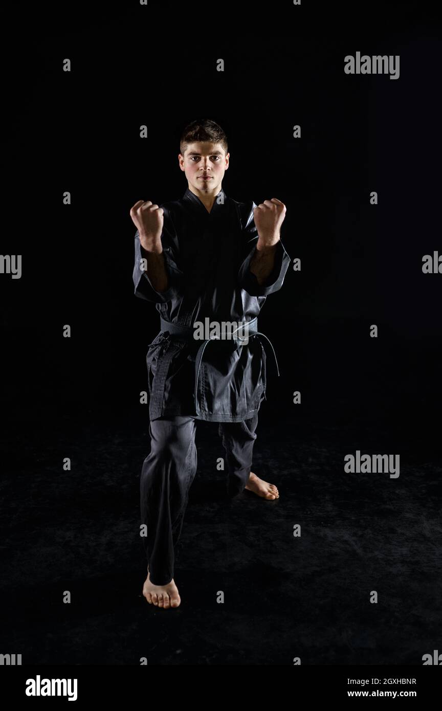 Male karate fighter in black kimono, combat stance, front view, dark ...