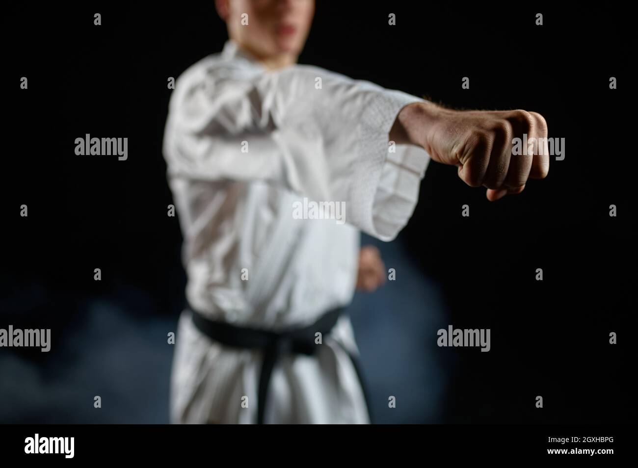 Male karateka, fighter practice in white kimono, combat stance, dark ...