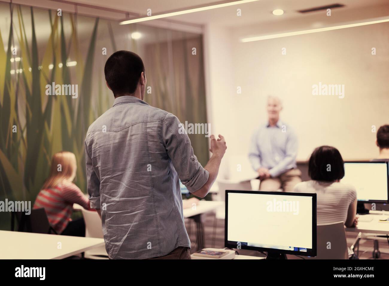 student answering a question in classroom, mature teacher and students ...