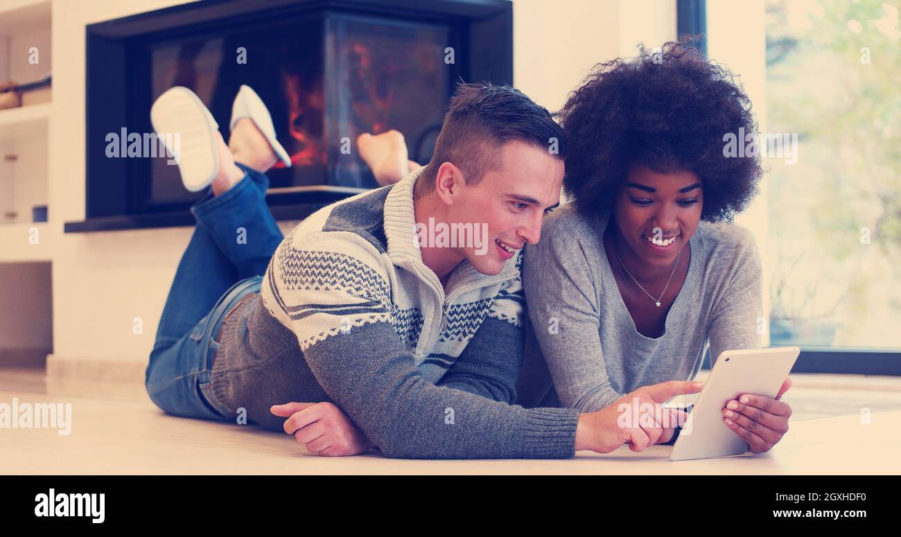 beautiful young multiethnic couple using tablet computer on the floor ...