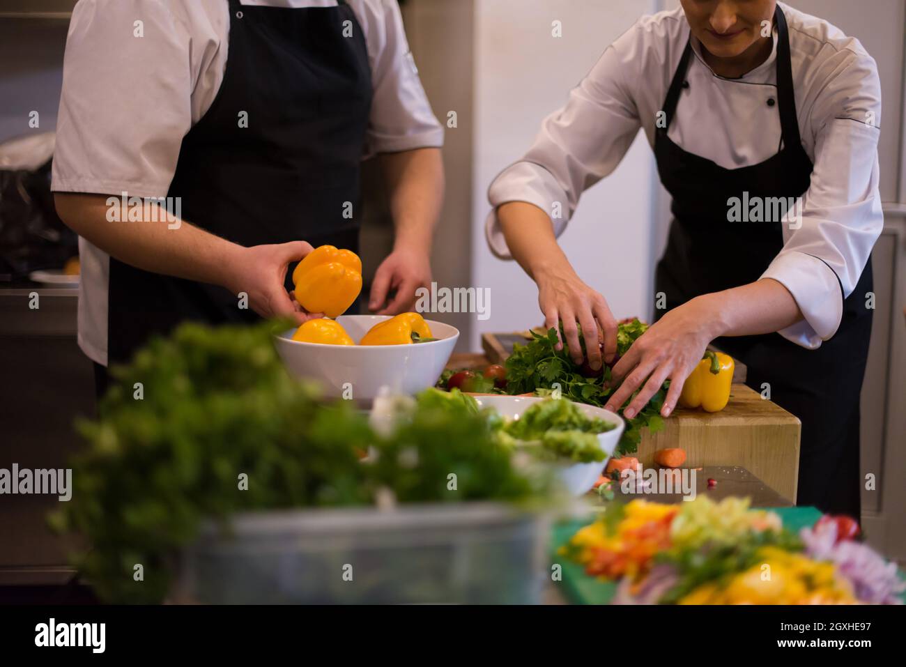 Professional team cooks and chefs preparing meal at busy hotel or ...