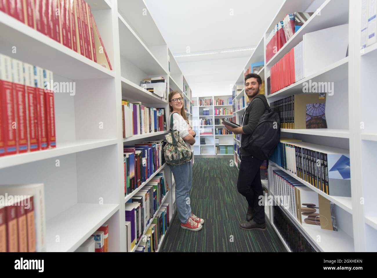 happy students group in school library selecting books to read and ...