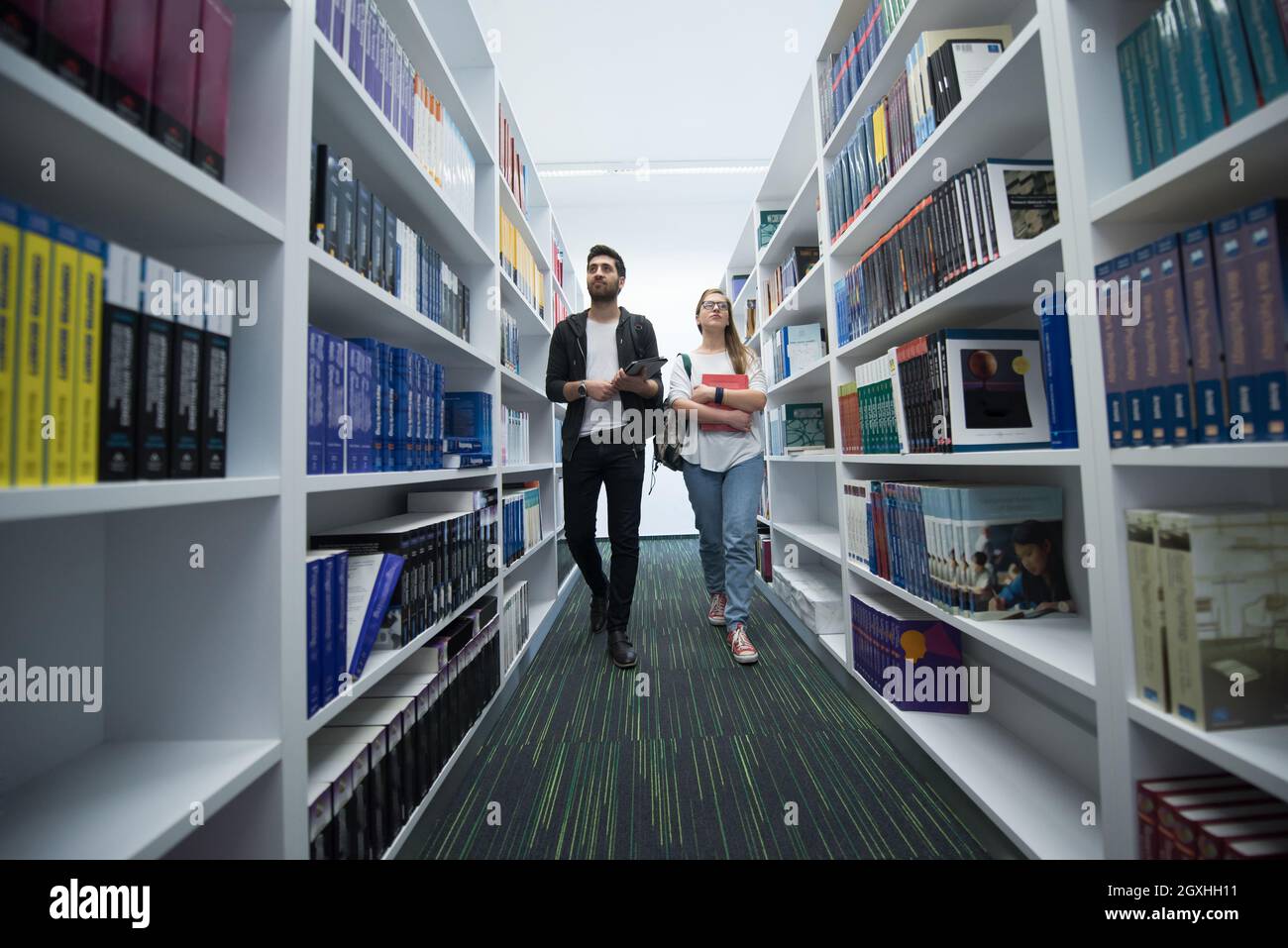 happy students group in school library selecting books to read and ...