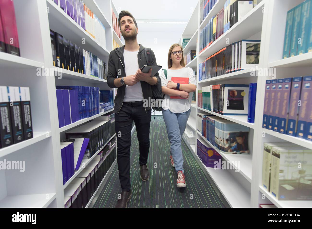 happy students group in school library selecting books to read and ...