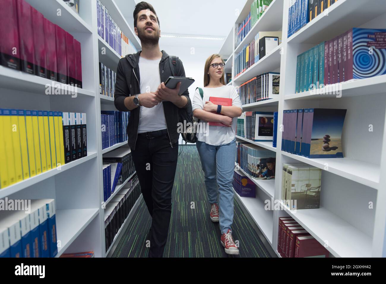 happy students group in school library selecting books to read and ...