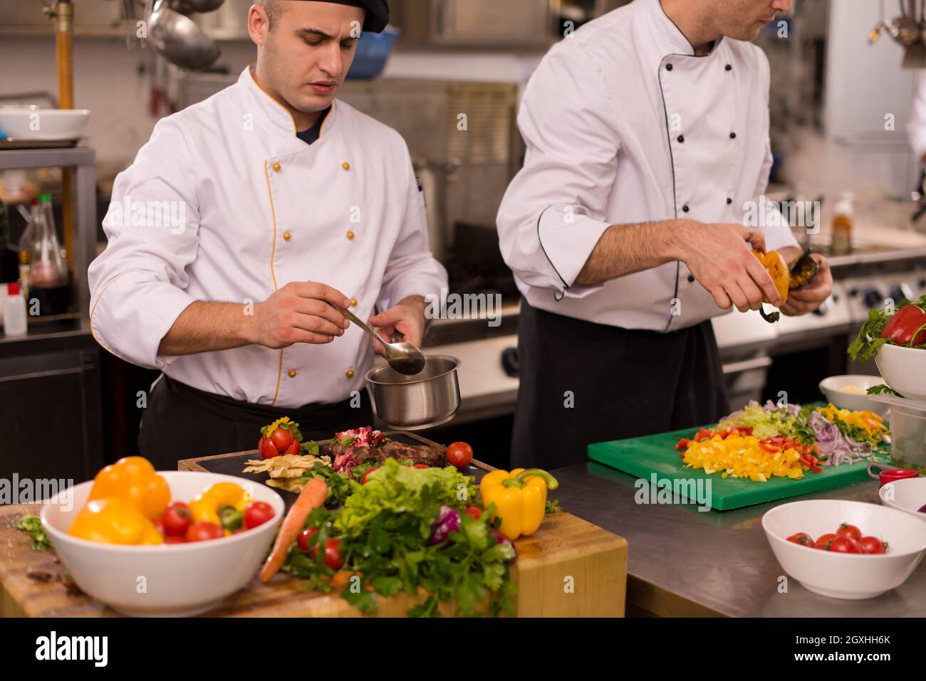 Professional team cooks and chefs preparing meal at busy hotel or ...