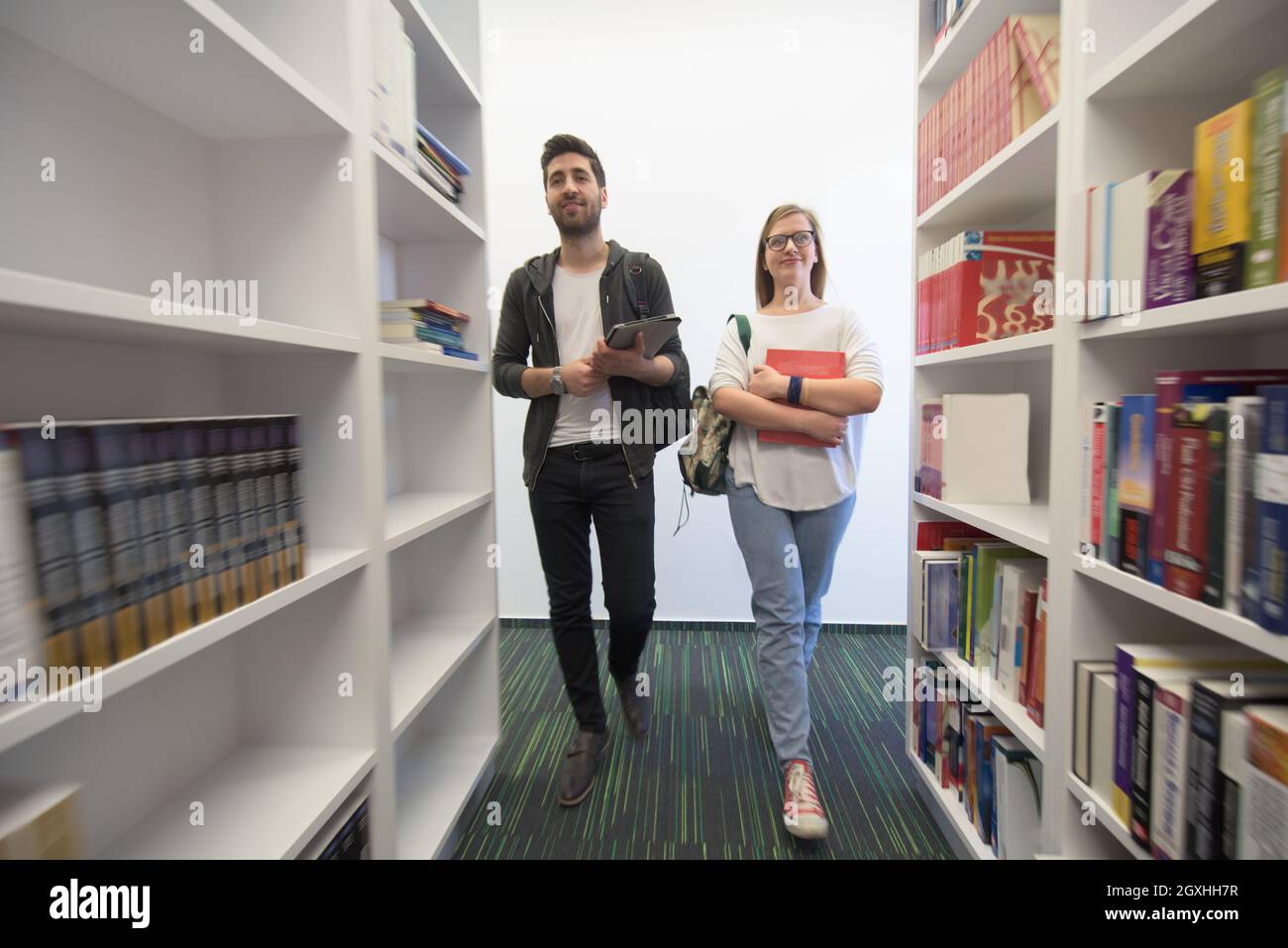 happy students group in school library selecting books to read and ...