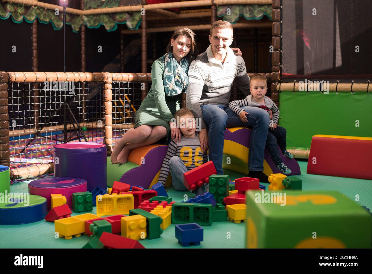 young happy parents having fun with kids in children playground indoor ...