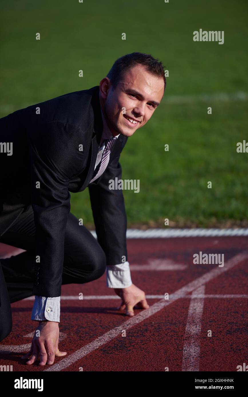 business man in start position ready to run and sprint on athletics ...