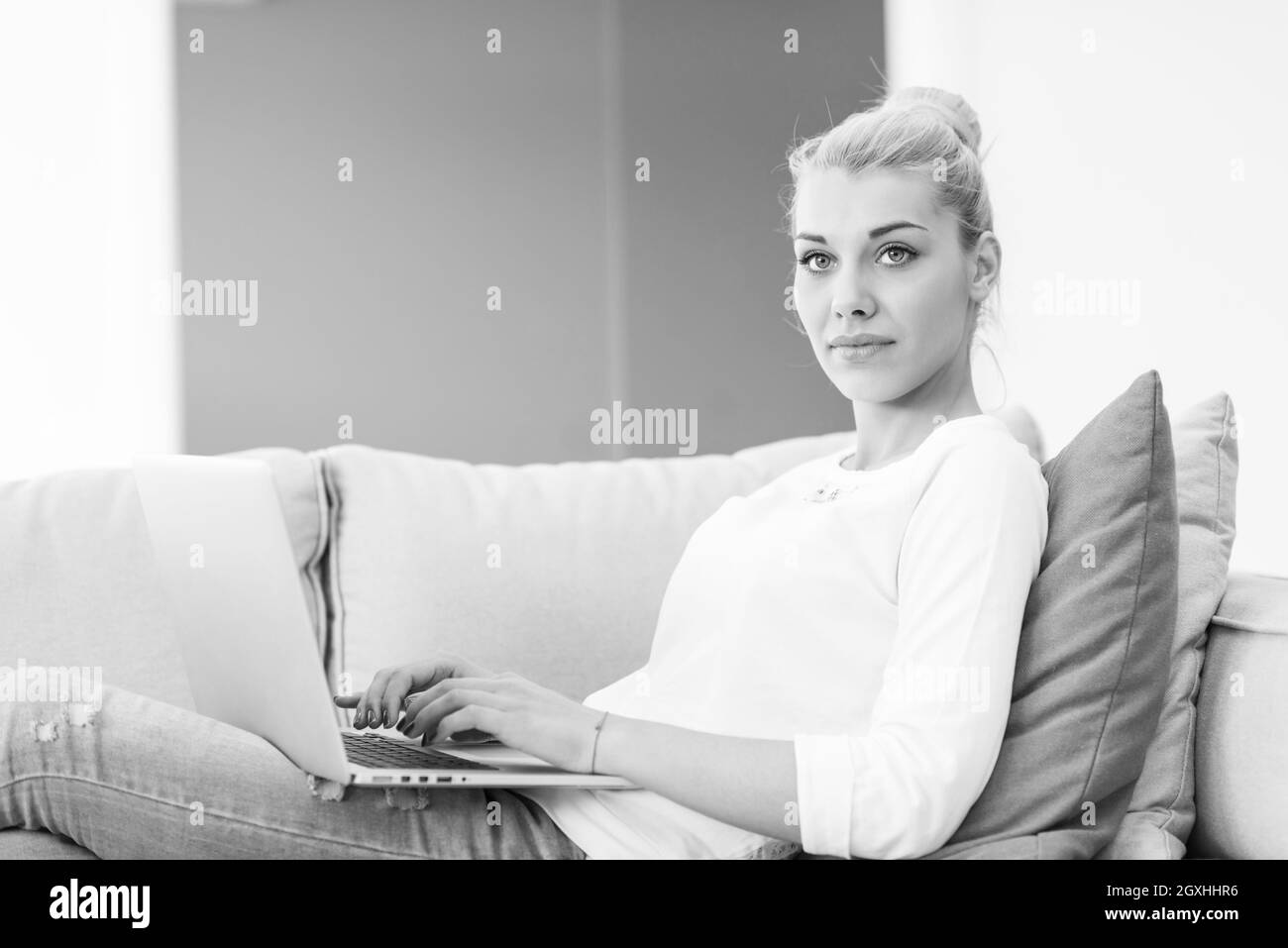 Young woman using her laptop computer in her luxury modern home ...