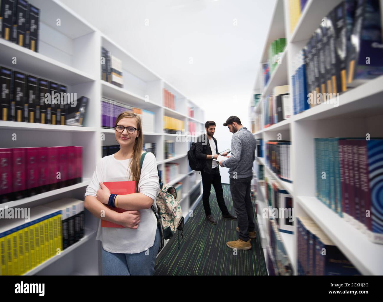 happy students group in school library selecting books to read and ...