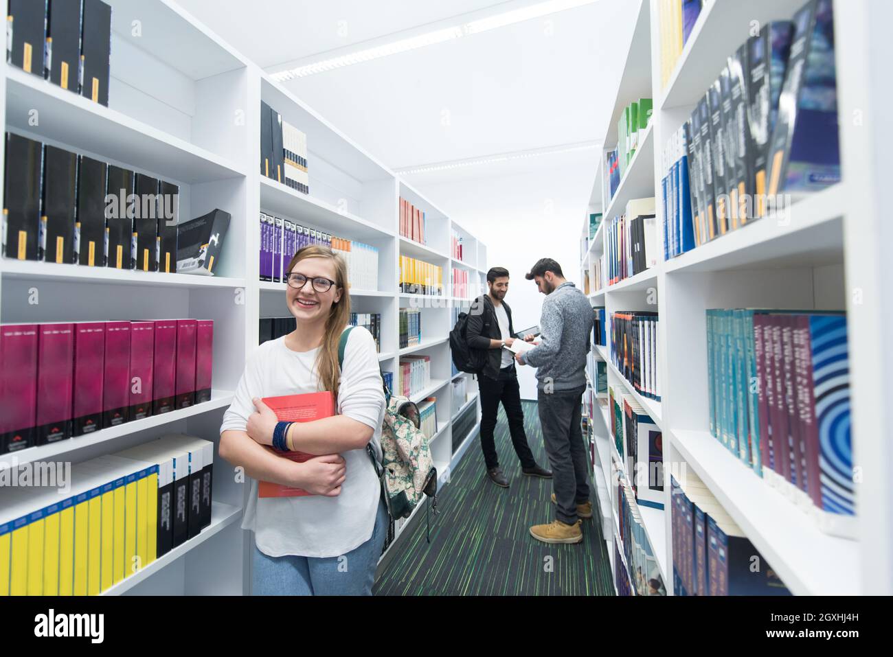 happy students group in school library selecting books to read and ...
