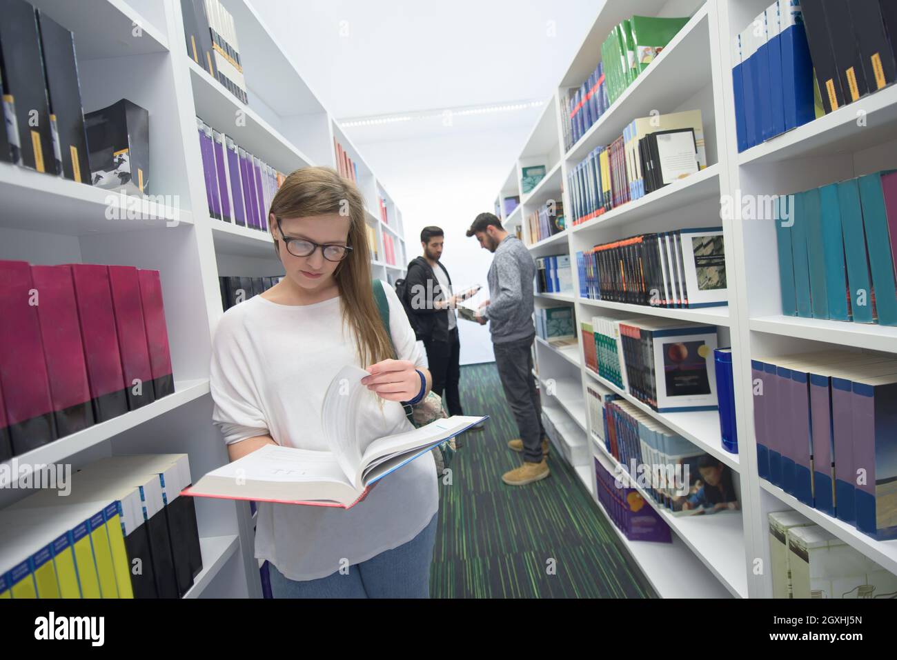 happy students group in school library selecting books to read and ...