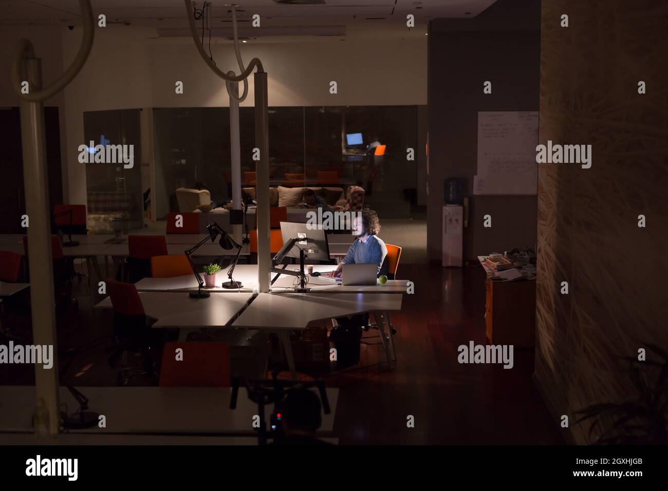 Young man working on computer at night in dark office. The designer ...