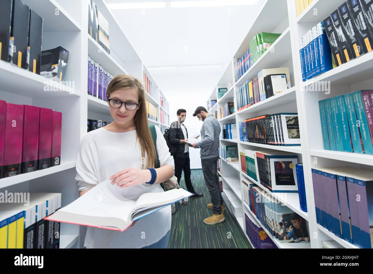 happy students group in school library selecting books to read and ...