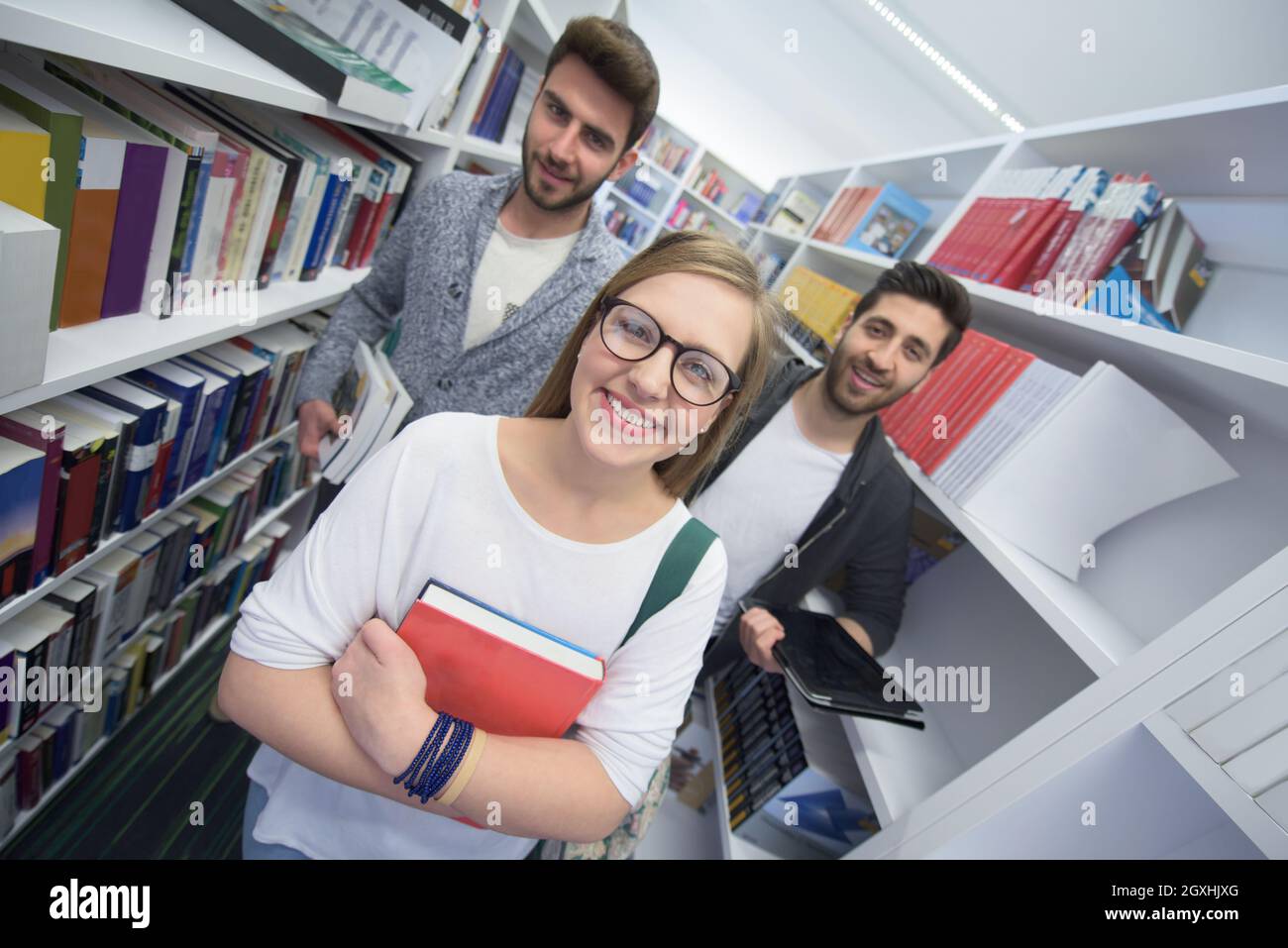 happy students group in school library selecting books to read and ...