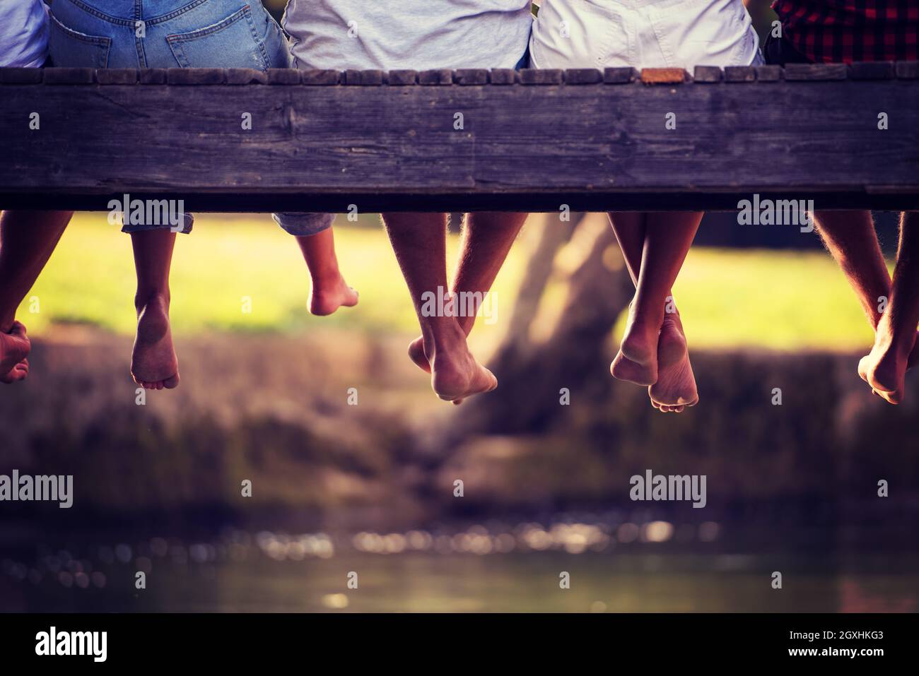 group of people sitting at wooden bridge over the river with a focus on ...