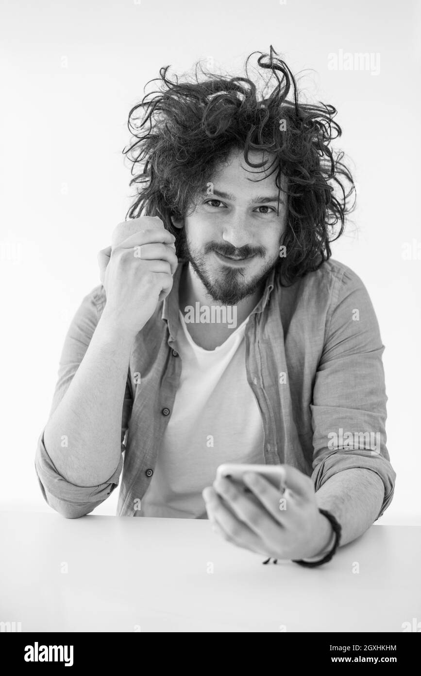 Handsome casual young man eating apple and using a mobile phone at home ...