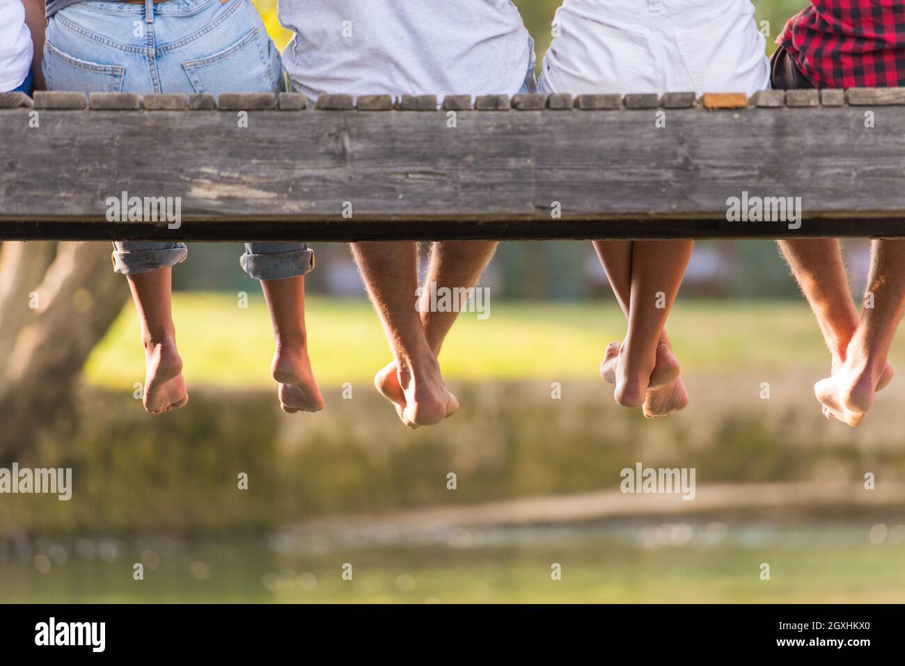 group of people sitting at wooden bridge over the river with a focus on ...