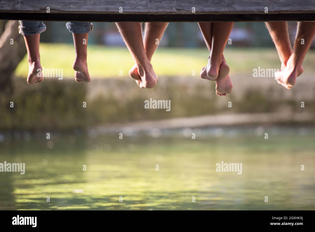 group of people sitting at wooden bridge over the river with a focus on ...