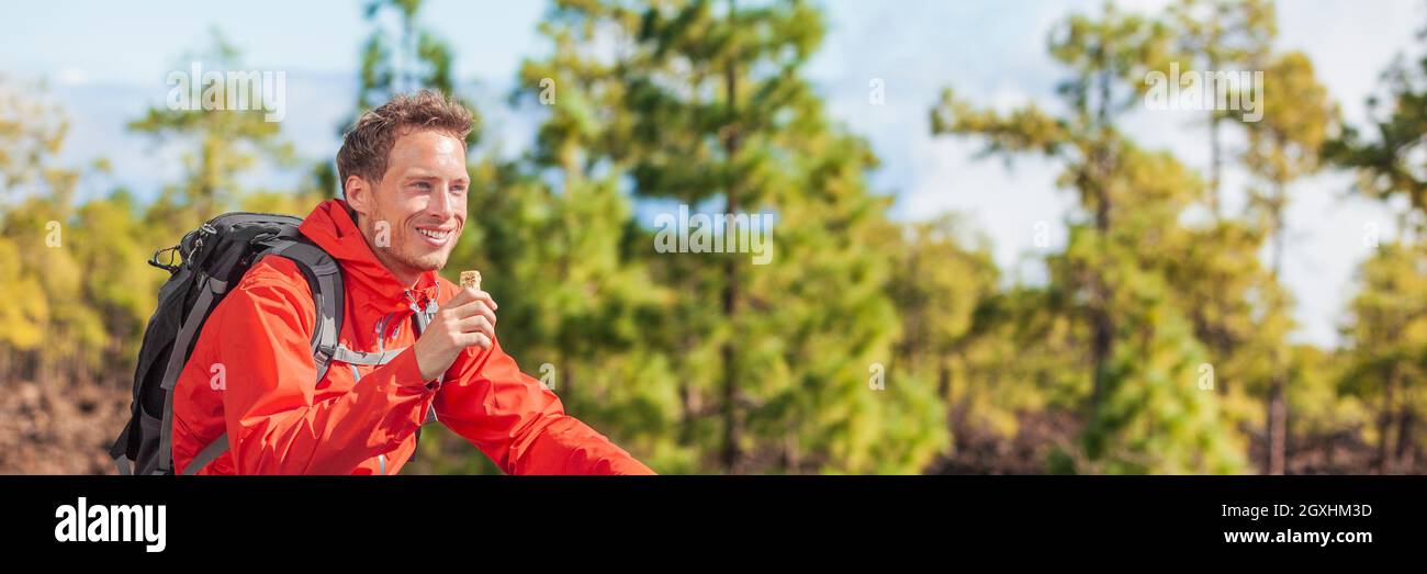 Eating granola bar snack on forest hike happy camper man hiking in ...