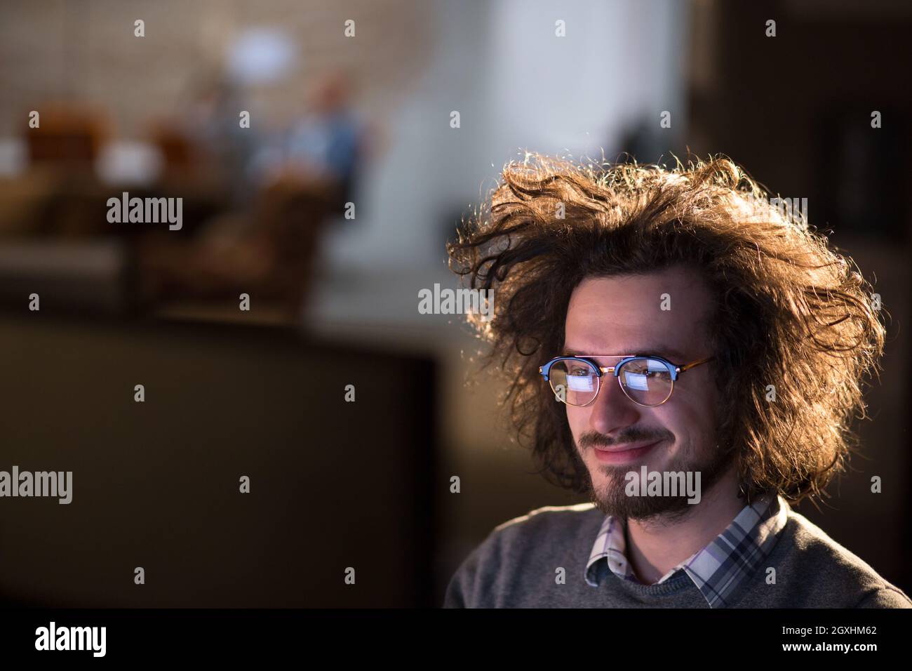 Young man working on computer at night in dark office. The designer ...