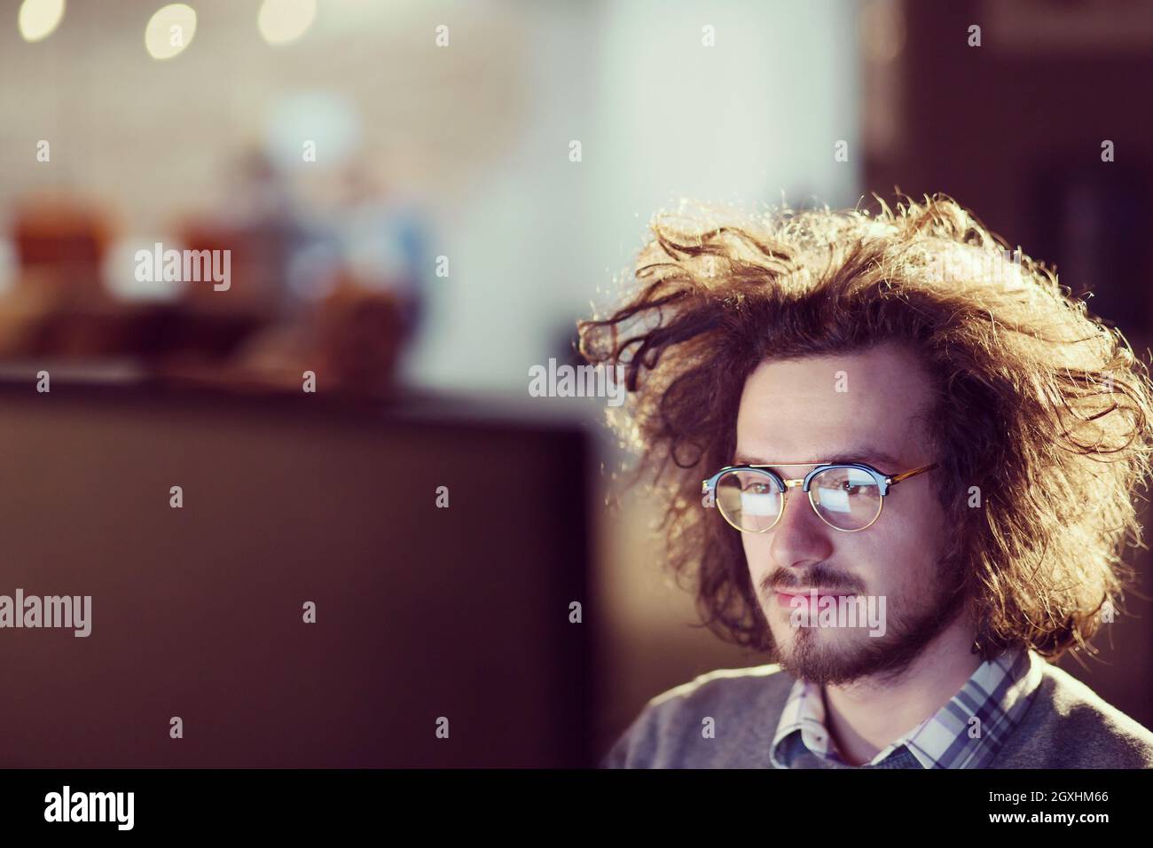 Young man working on computer at night in dark office. The designer ...