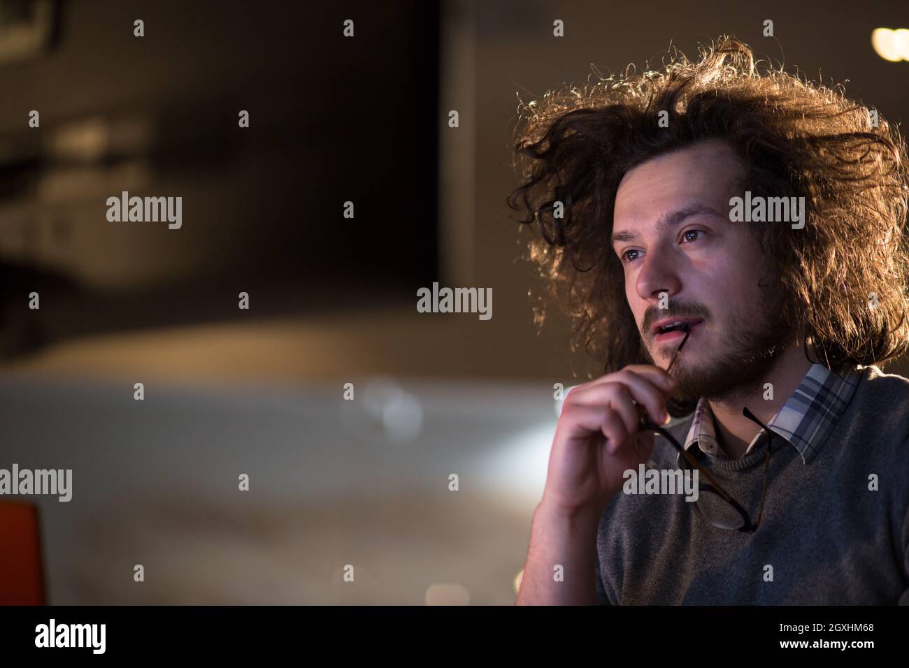 Young man working on computer at night in dark office. The designer ...