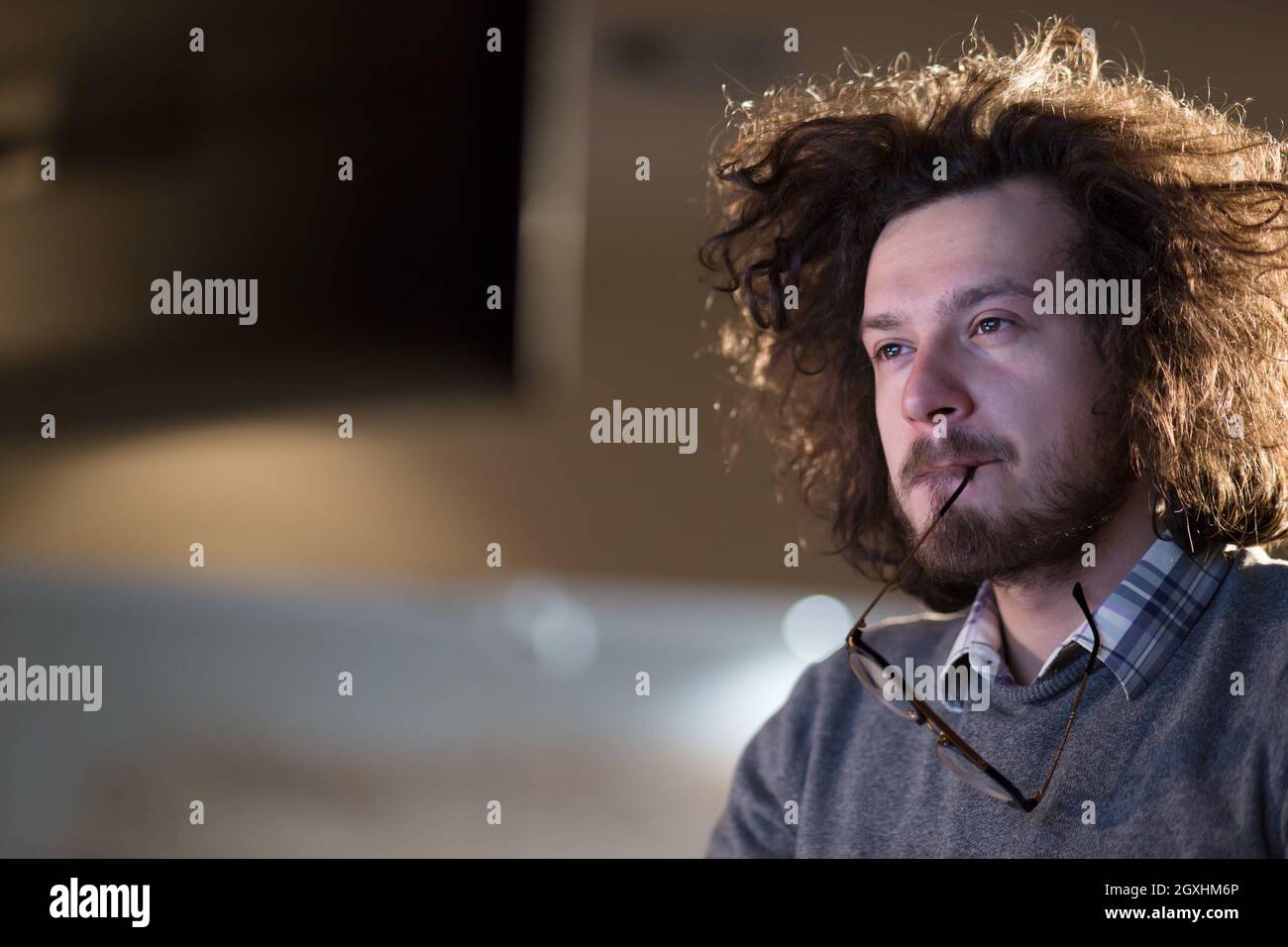 Young man working on computer at night in dark office. The designer ...