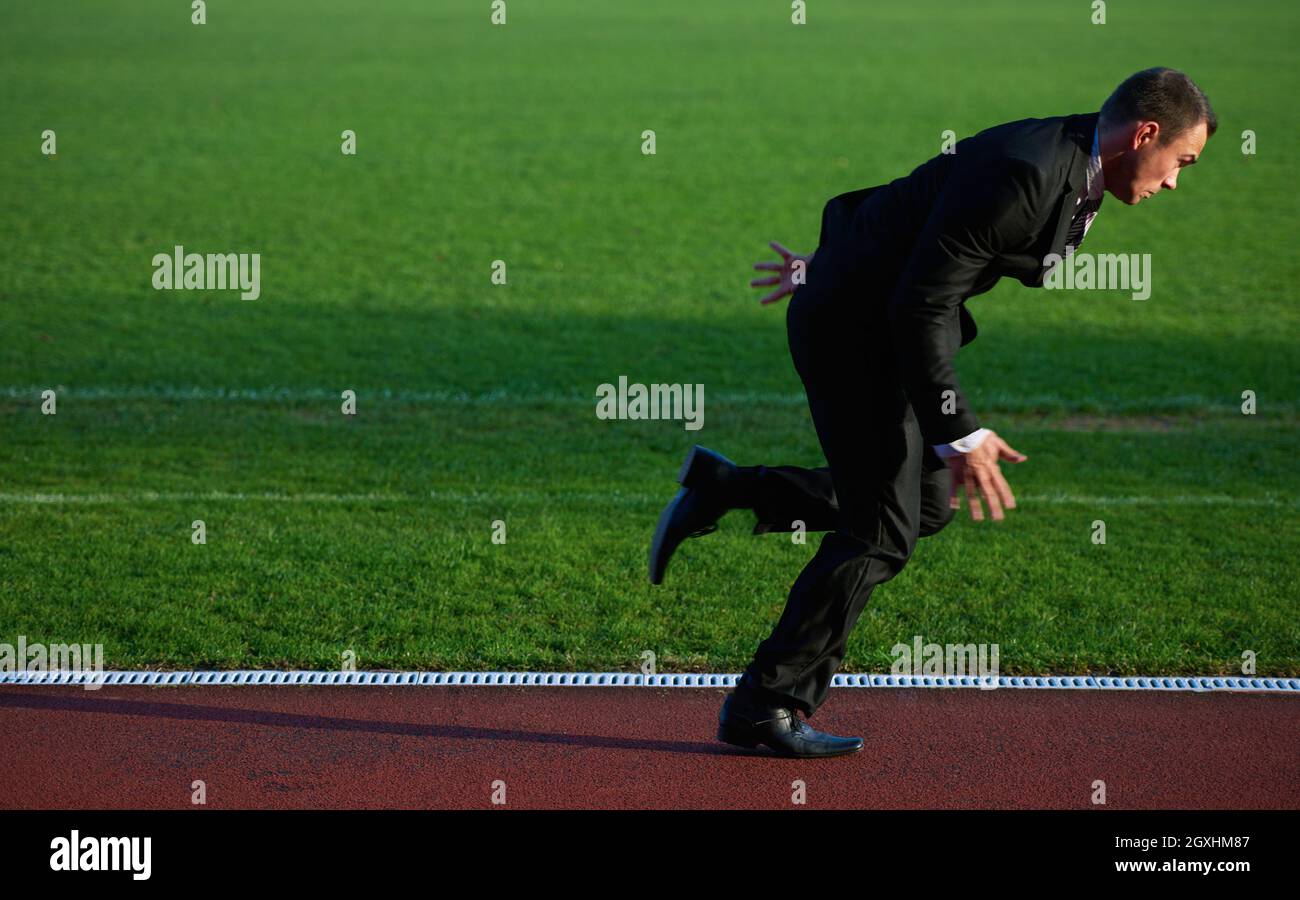 business man in start position ready to run and sprint on athletics ...