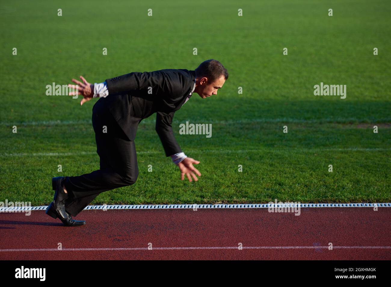 business man in start position ready to run and sprint on athletics ...