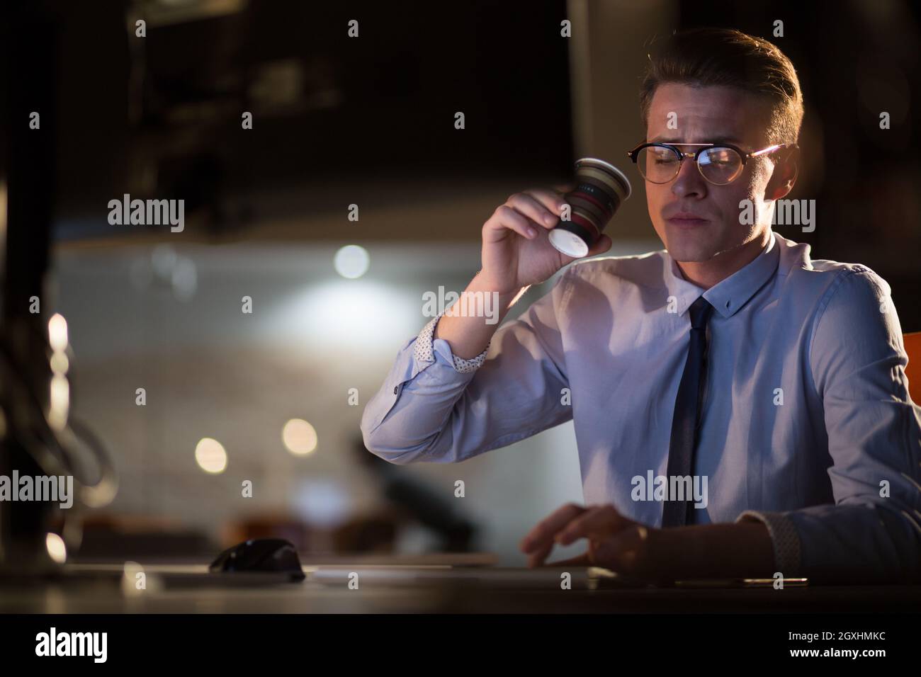 Tired businessman working late doing overtime in office at night ...