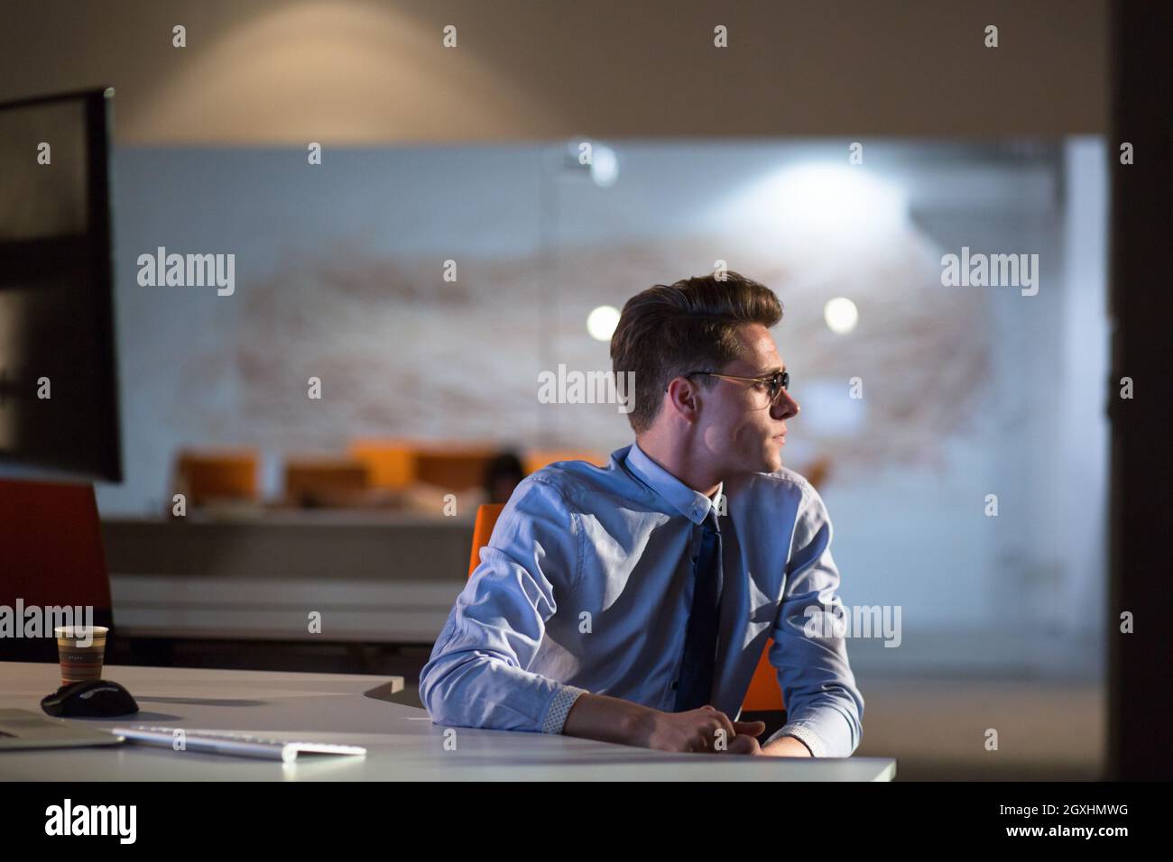 Young man working on computer at night in dark office. The designer ...