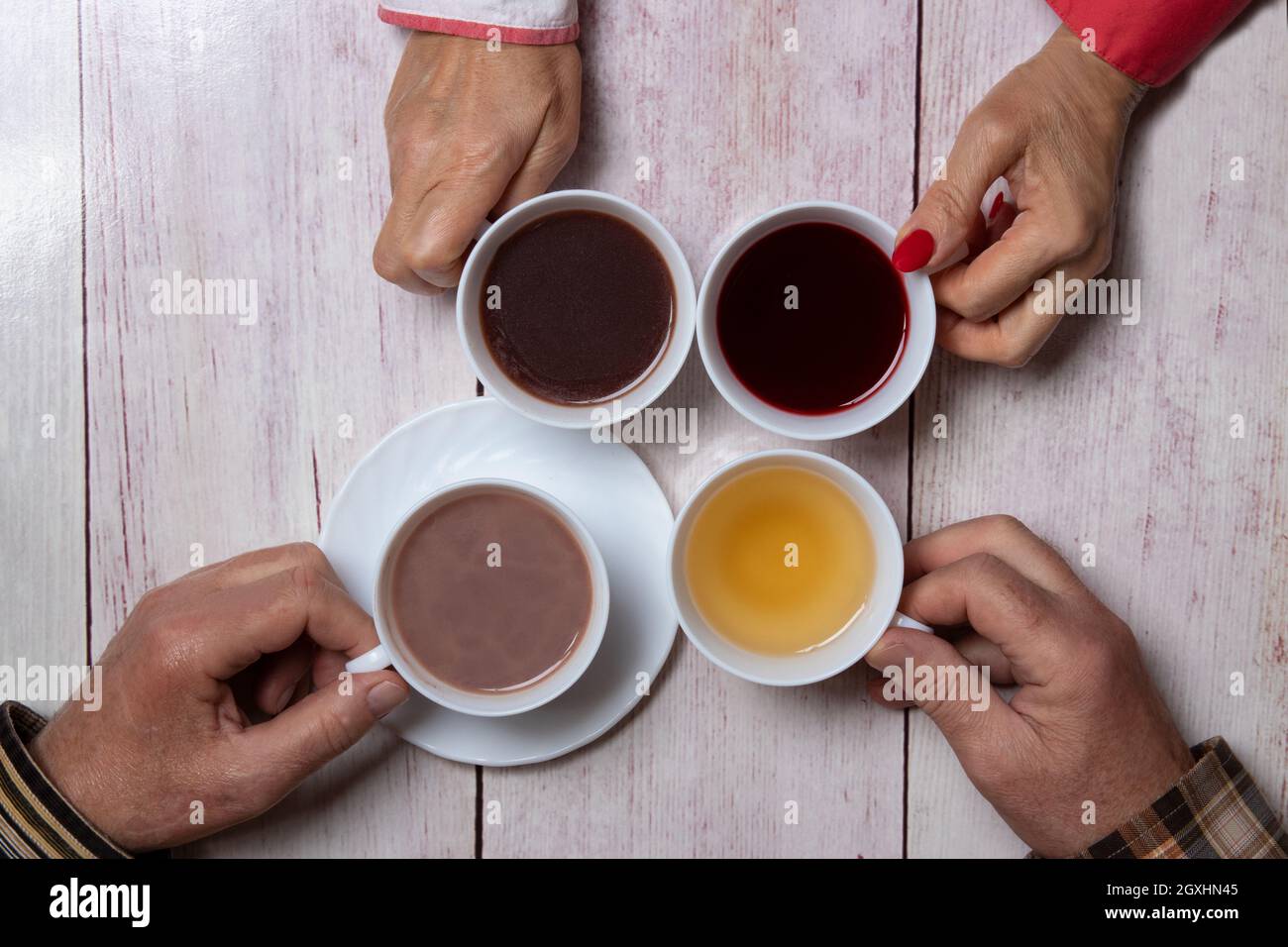 People drinking coffee and tea. Top view of the hands of four people ...