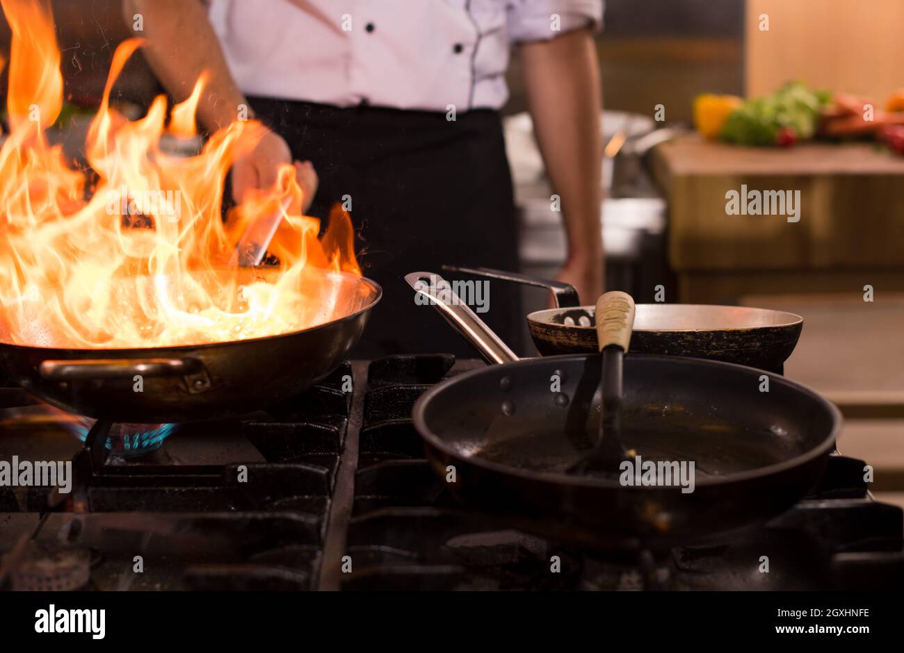 Chef cooking and doing flambe on food in restaurant kitchen Stock Photo ...