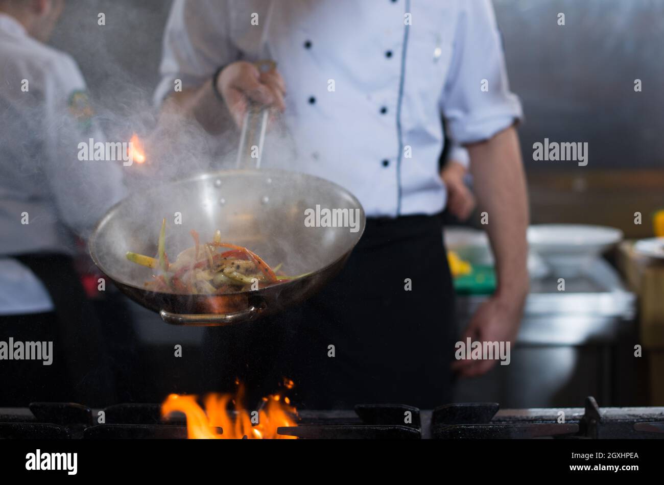 Chef cooking and doing flambe on food in restaurant kitchen Stock Photo ...