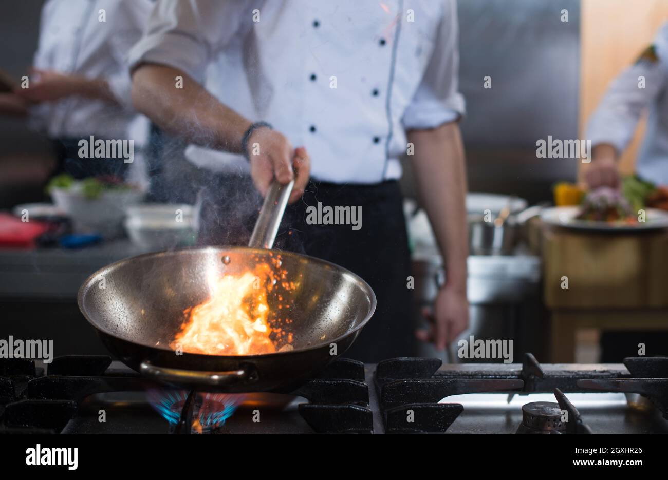 Chef cooking and doing flambe on food in restaurant kitchen Stock Photo ...