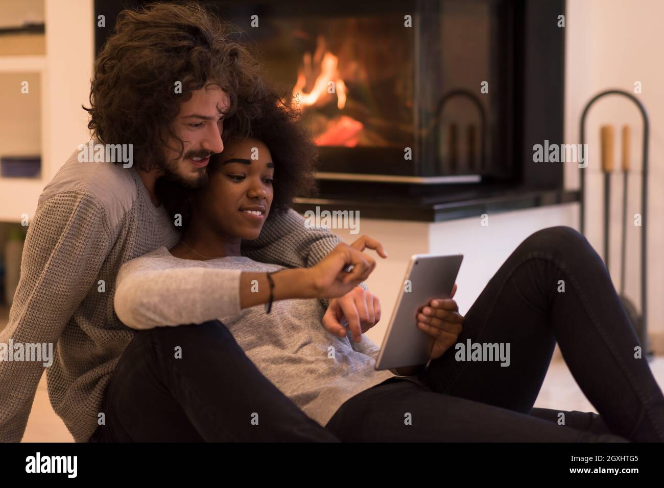 beautiful young multiethnic couple using tablet computer on the floor ...