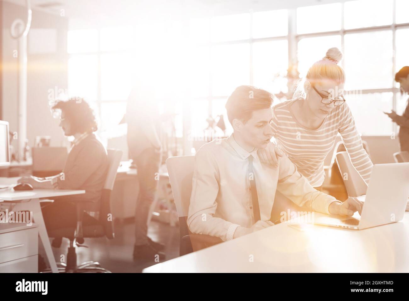Young businesswoman helping his colleague to fix the problem at the ...