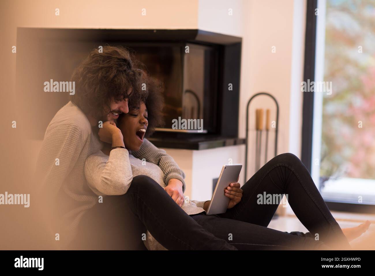 beautiful young multiethnic couple using tablet computer on the floor ...