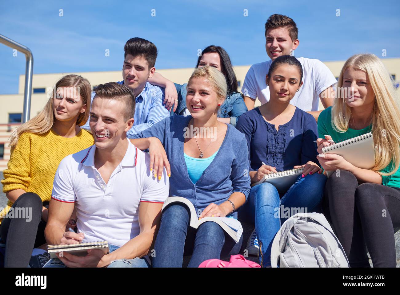 Group portrait of happy students outside sitting on steps have fun ...