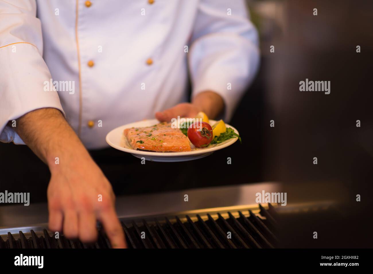 Master chef hands cooking grilled salmon fish with potatoes on a ...