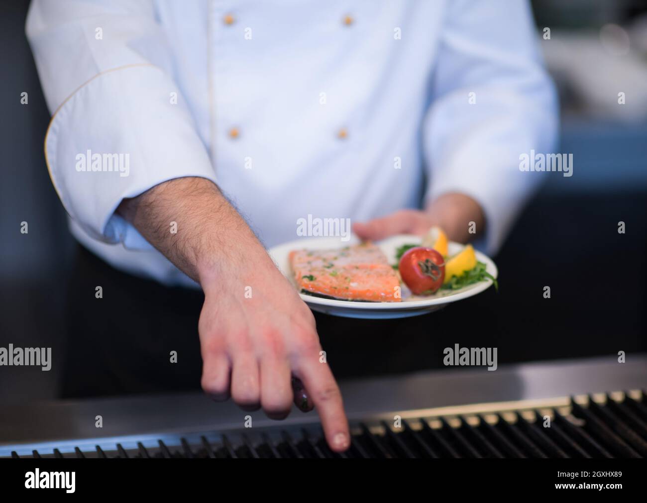 Master chef hands cooking grilled salmon fish with potatoes on a ...