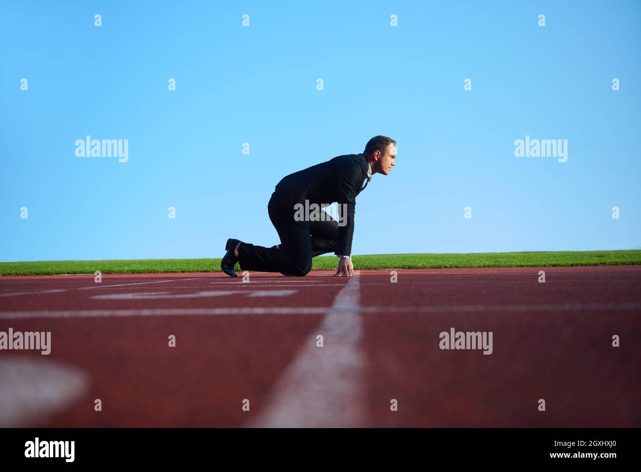 business man in start position ready to run and sprint on athletics ...