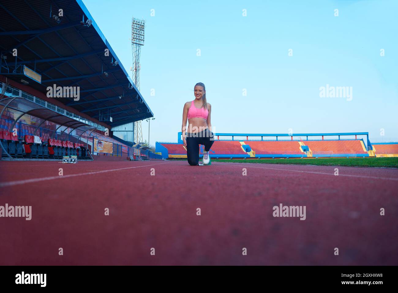 woman sprinter leaving starting blocks on the athletic track. Side view ...