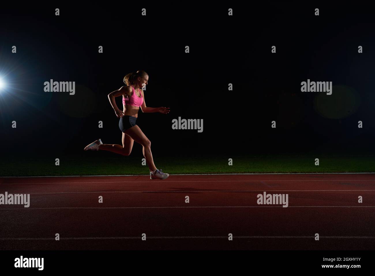 Athletic woman running onrace track Stock Photo - Alamy