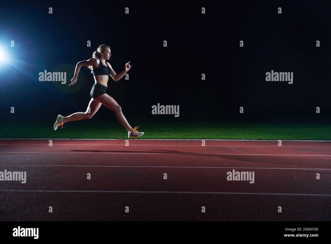 Athletic woman running onrace track Stock Photo - Alamy