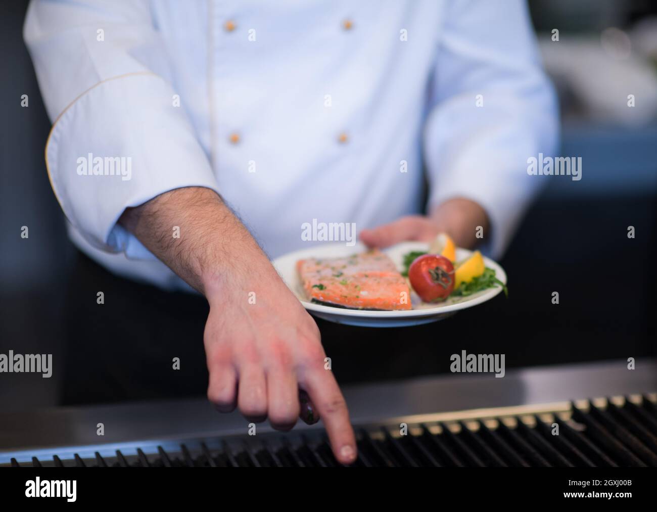 Master chef hands cooking grilled salmon fish with potatoes on a ...
